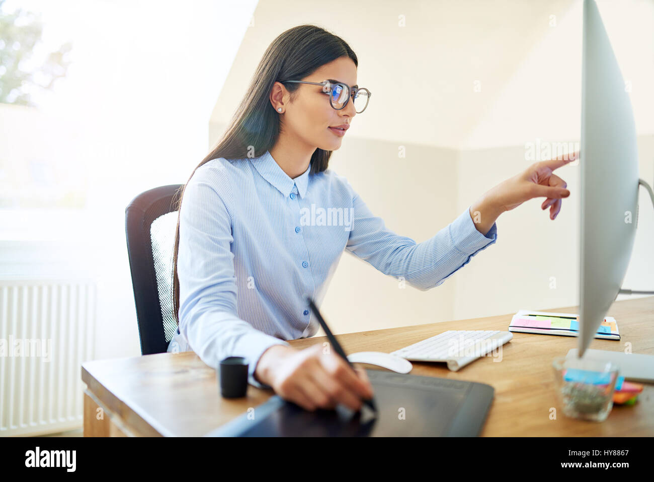 Beautiful young digital artist pointing at monitor display while ...