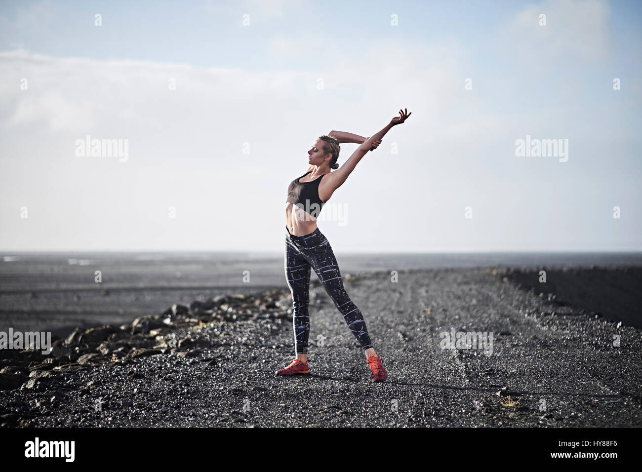 Young women stretching on a deserted unmade road in Southern Iceland ...