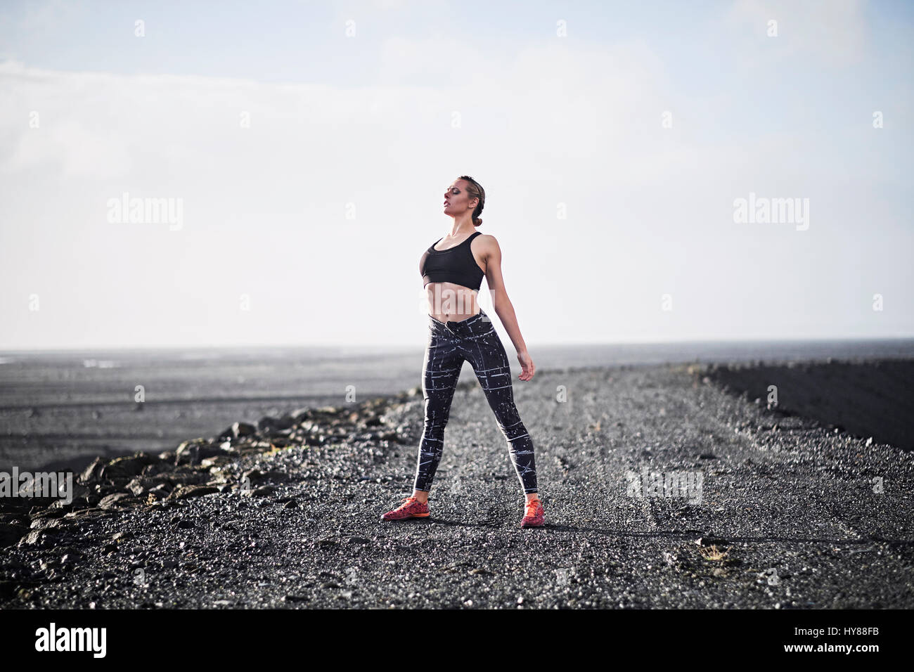 Young women stretching on a deserted unmade road in Southern Iceland ...