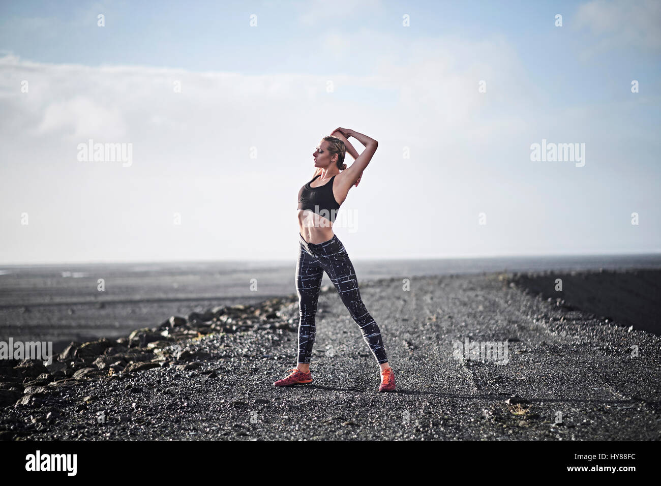 Young women stretching on a deserted unmade road in Southern Iceland ...