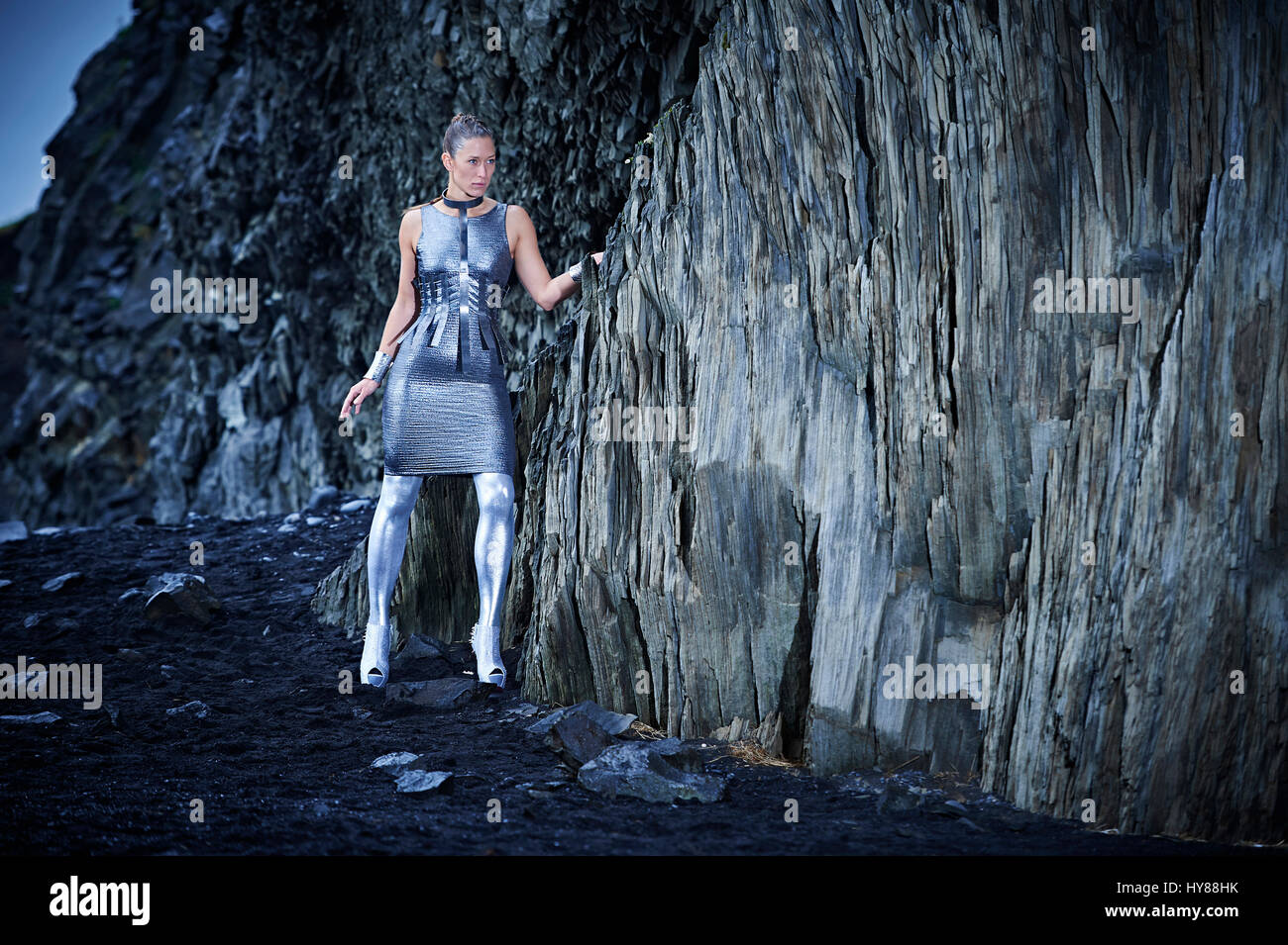 Young women in silver outfit walking with caution into a cave in ...