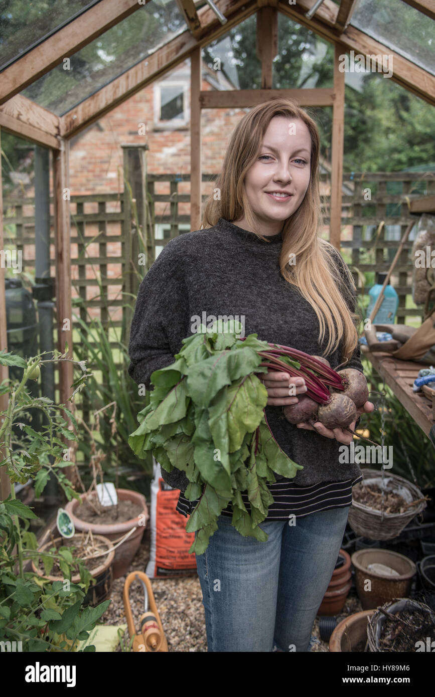 A young female gardener works in her greenhouse Stock Photo - Alamy