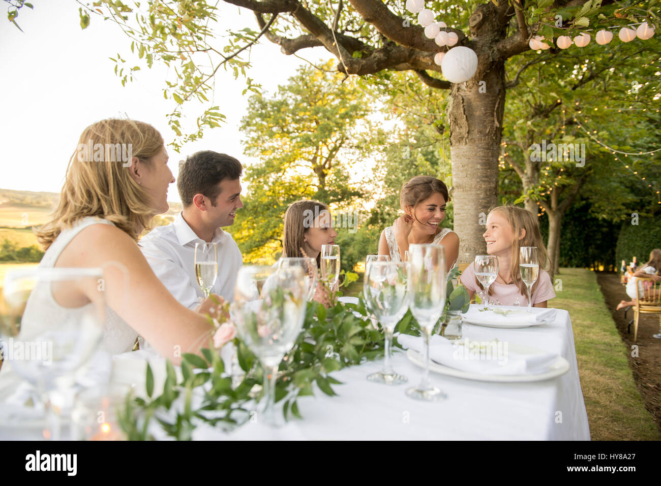 A bride and groom sitting at the top table with their friends at an ...