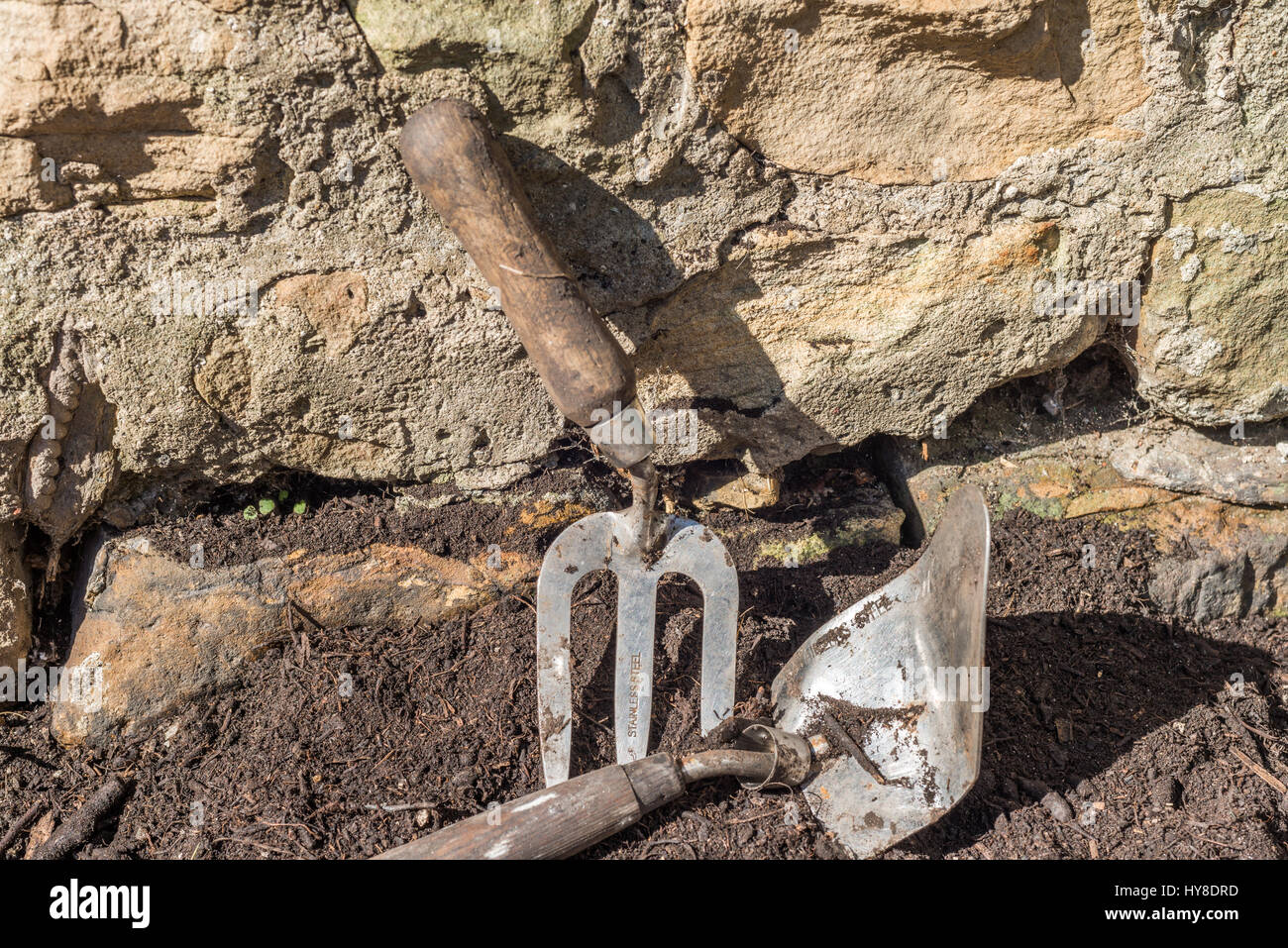 Old and misshaped garden tools against a stone wall Stock Photo - Alamy