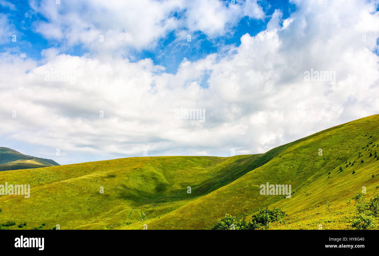 deep blue sky with some clouds over the green and grassy hills of ...