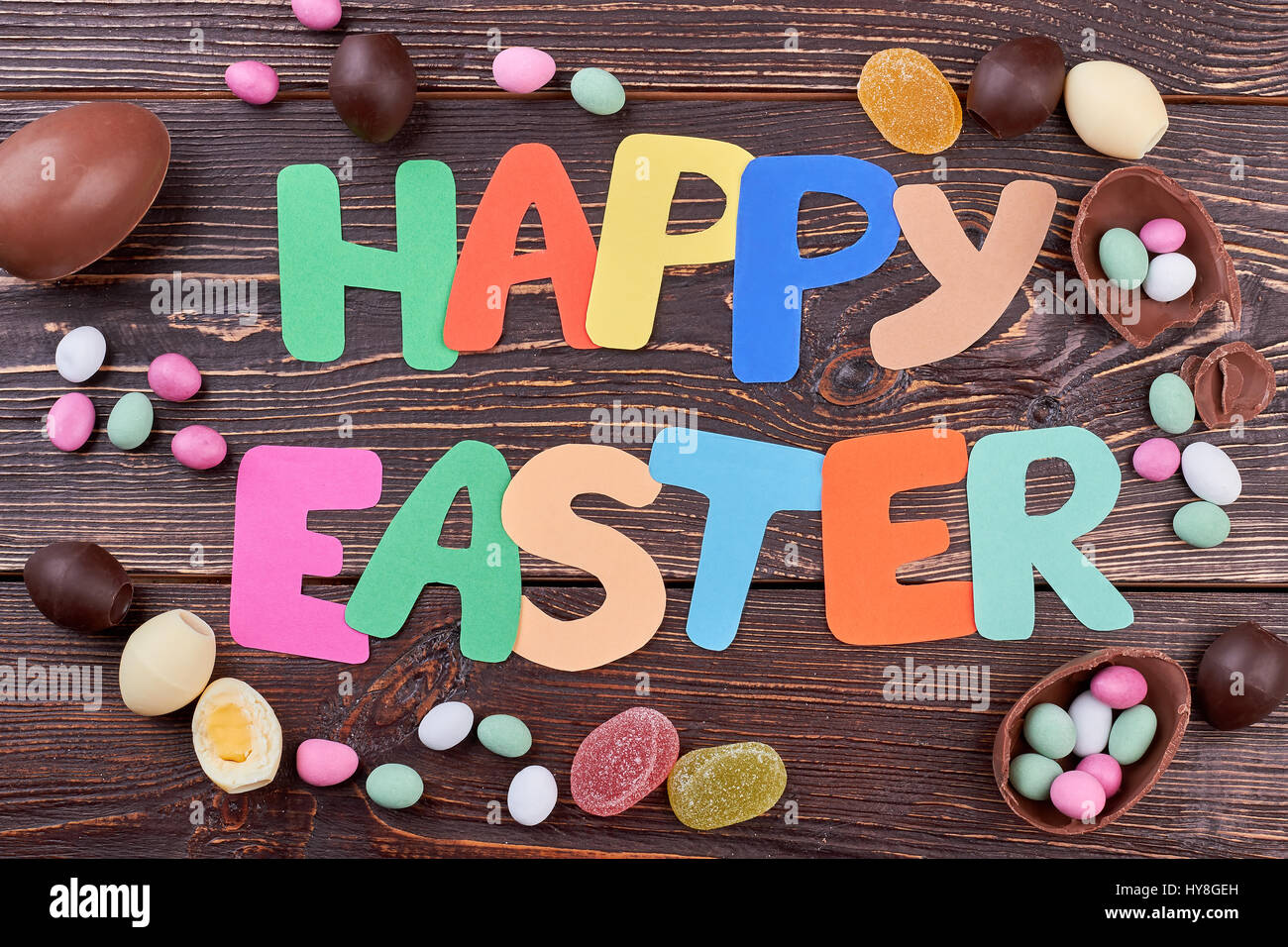 Happy Easter lettering and sweets. Candies on brown wood Stock Photo ...