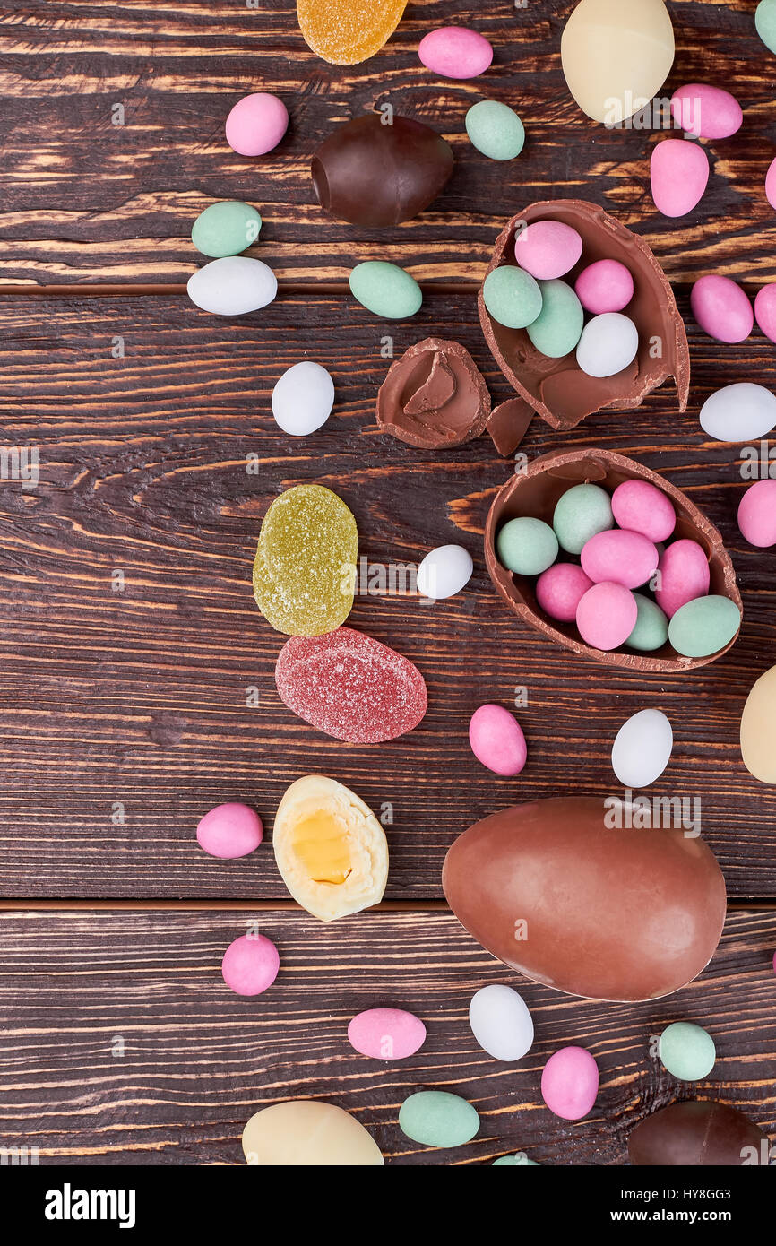 Wooden background with candies. Broken chocolate egg and sweets Stock ...