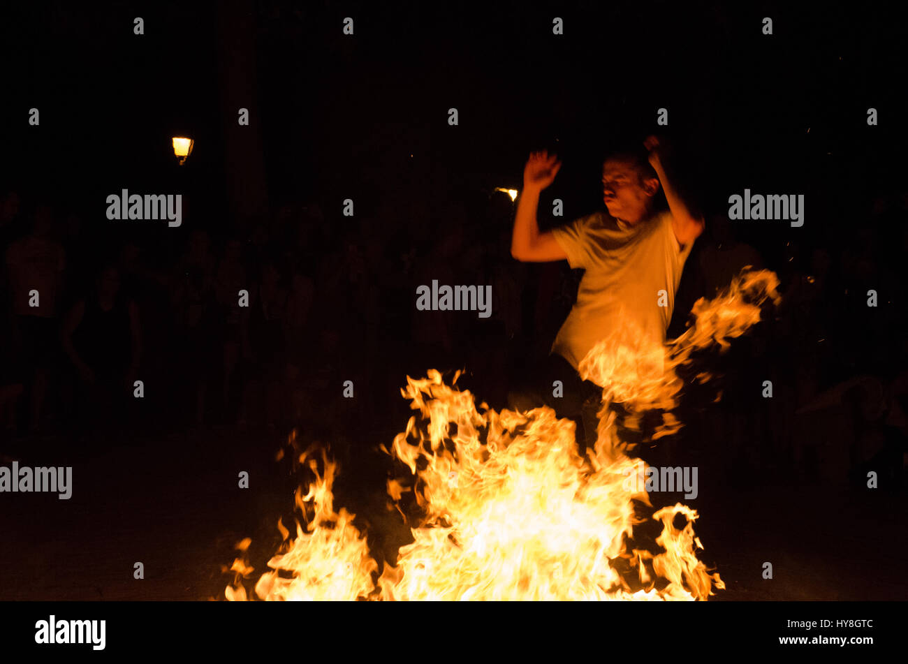 Close up of a man jumping through the fire of a bonfire during Saint ...