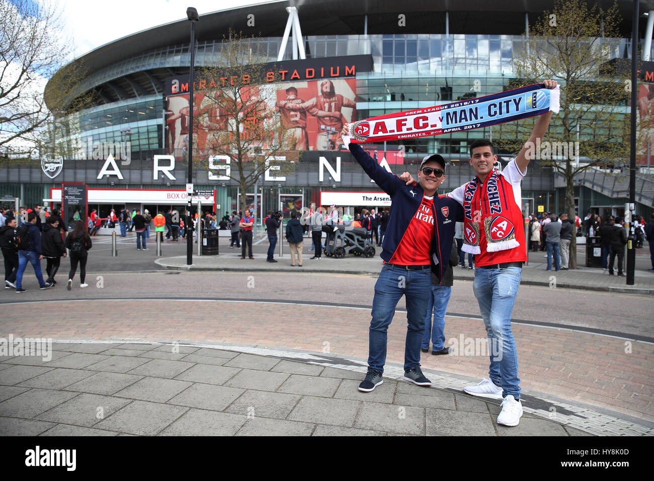 Arsenal fans pose for a picture holding scarves outside the ground ...