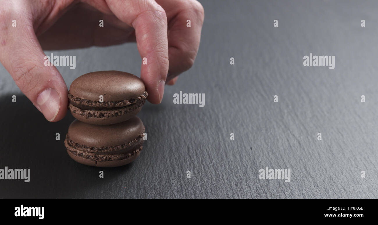 man hand stacking chocolate macarons on slate board, 4k photo Stock ...