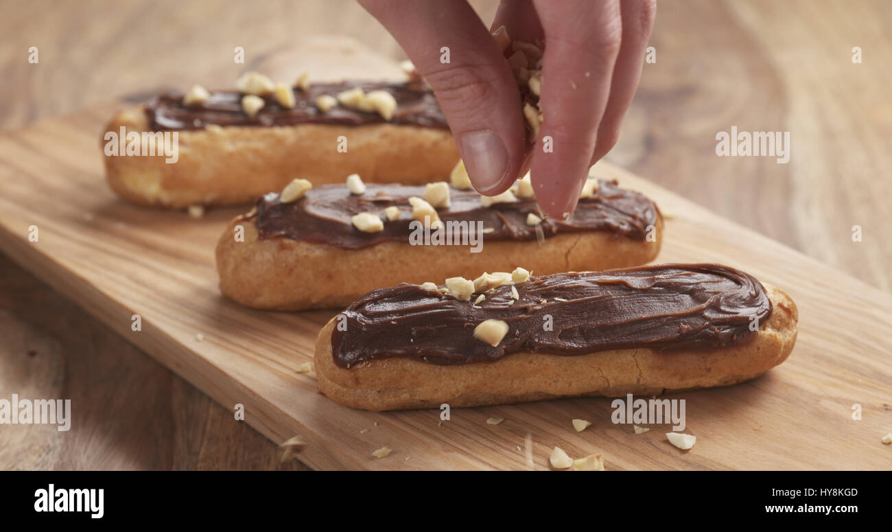 decorating eclairs with hazelnuts on wood board, 4k photo Stock Photo ...