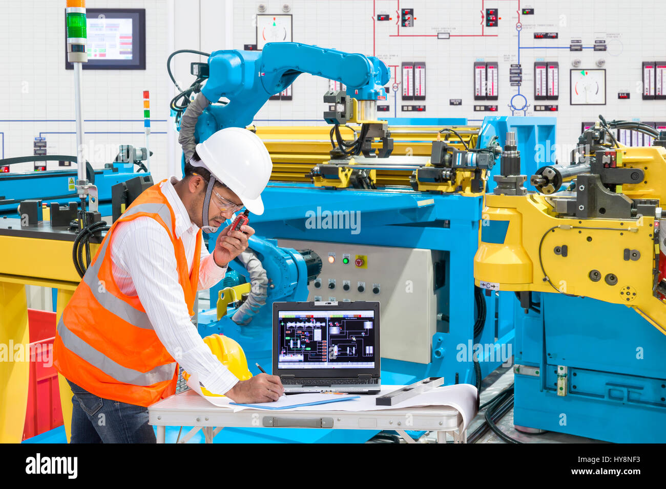 Engineer using laptop computer for maintenance automatic robotic hand machine tool at industrial ...