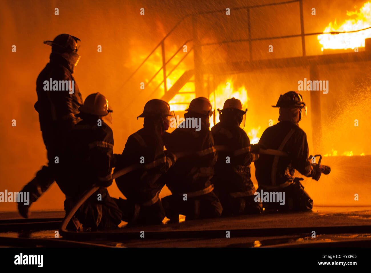 Fire chief and firefighters in front of burning structure during ...