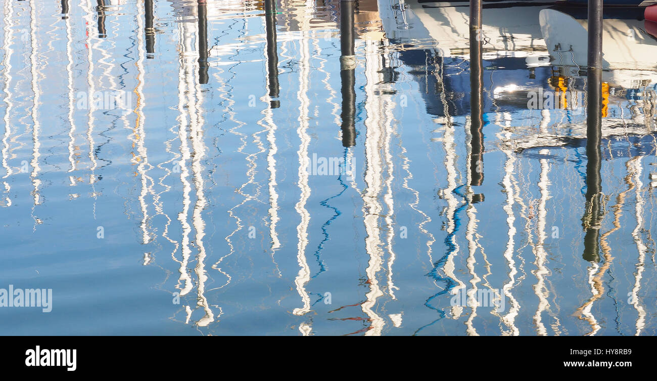Reflections of sailing boats in a marina, sunny summer day, using as an ...