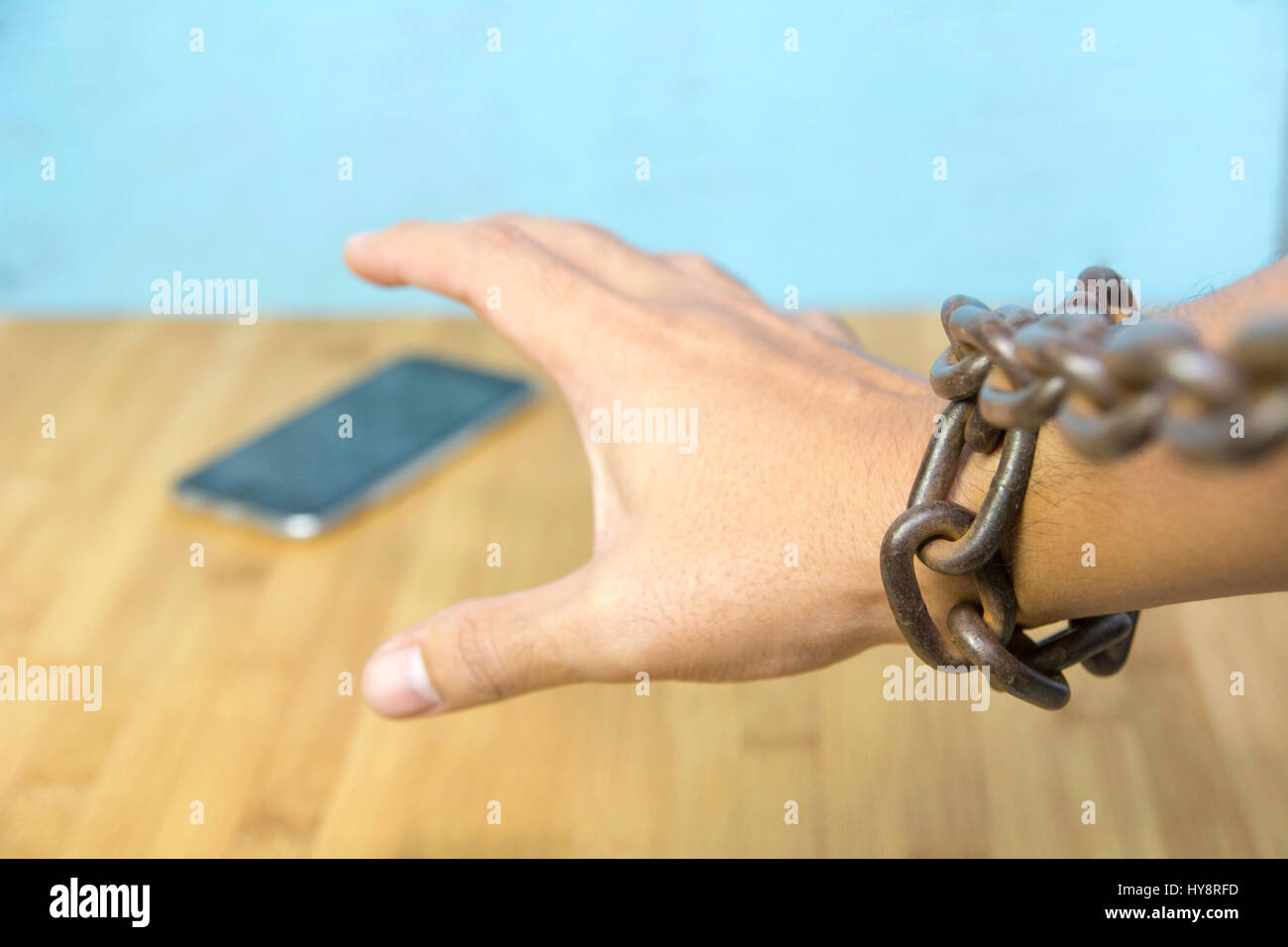 Chained human hand trying to catch smart phone on table. Concept of ...