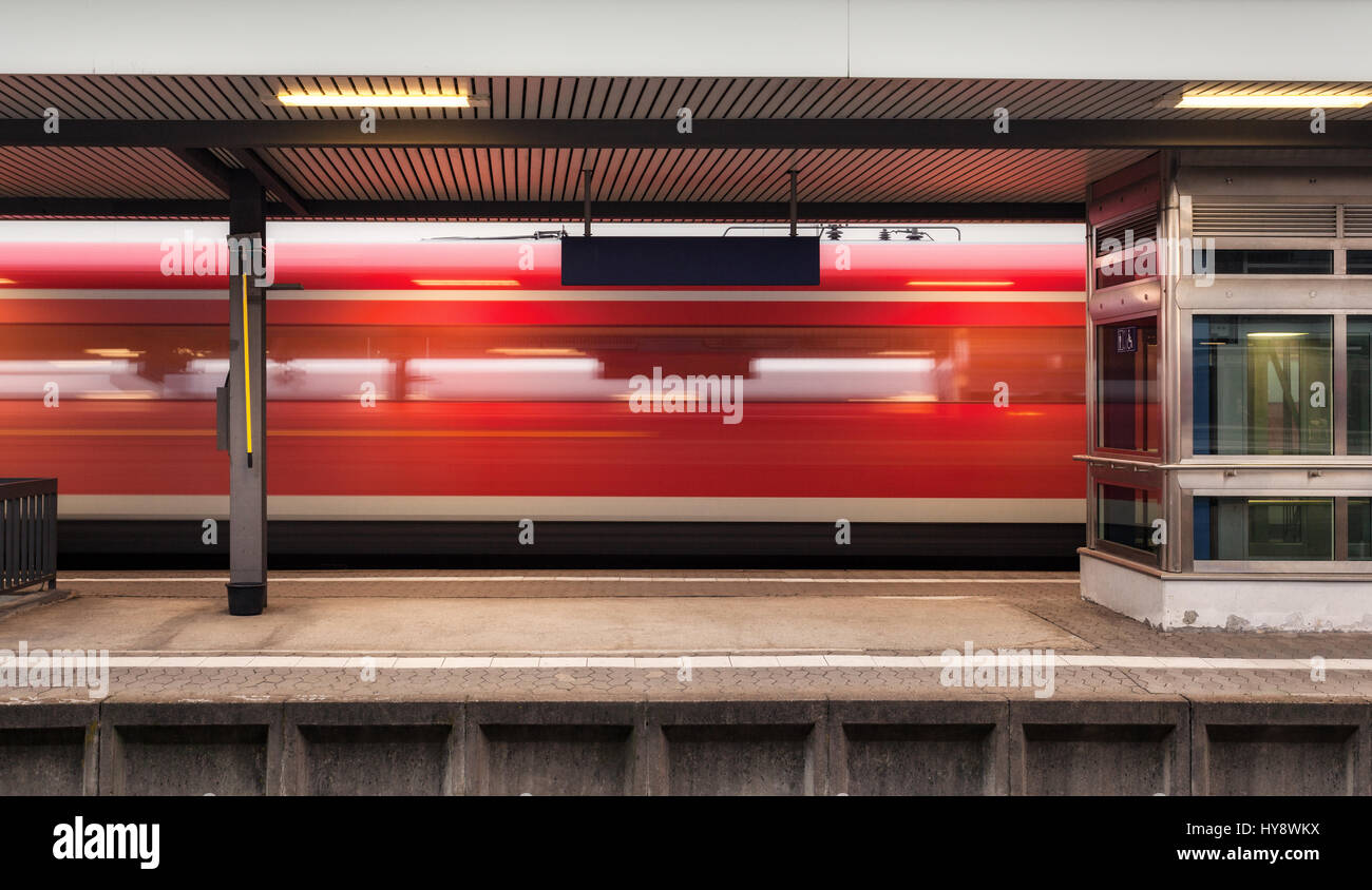 Railway platform with high speed red passenger train in motion in ...