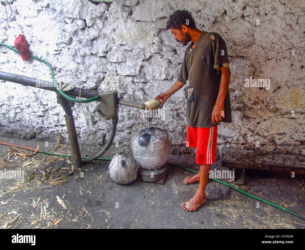 A man distills grogue, a local alcoholic liquor, from crushed sugar ...