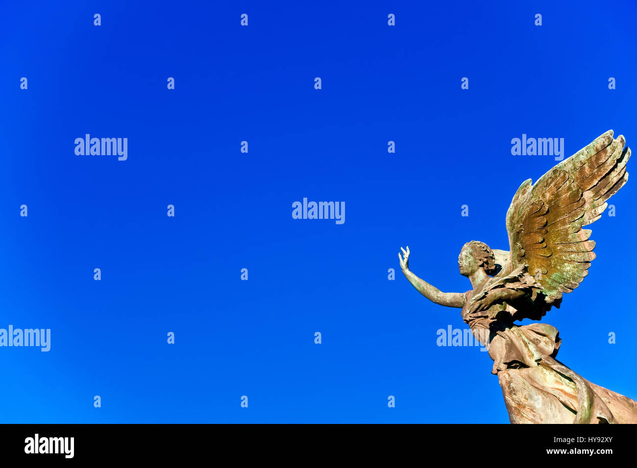 Statue of a winged woman, like an angel, standing out from the blue sky ...