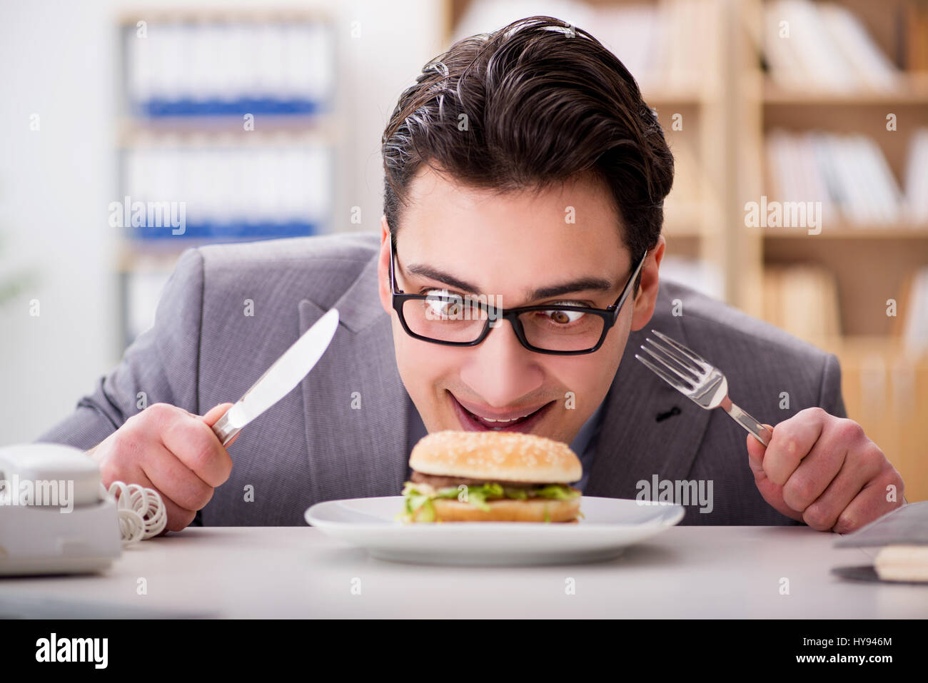 Hungry funny businessman eating junk food sandwich Stock Photo - Alamy