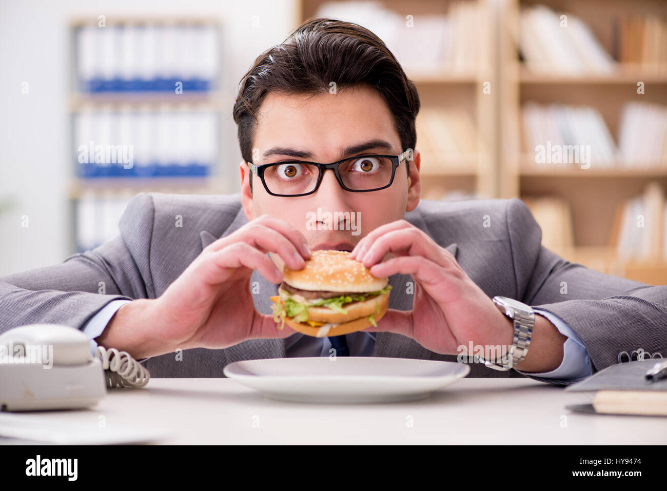 Hungry funny businessman eating junk food sandwich Stock Photo - Alamy