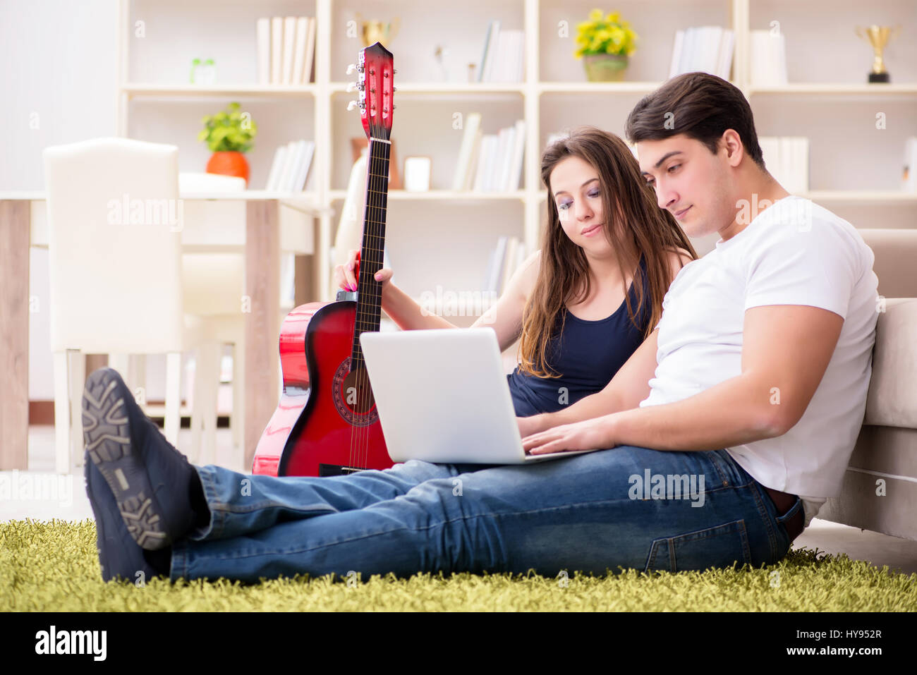 Romantic pair playing guitar on floor Stock Photo - Alamy