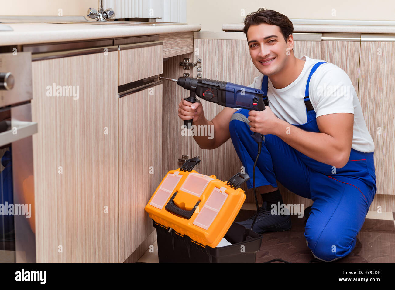 Young repairman working at the kitchen Stock Photo - Alamy