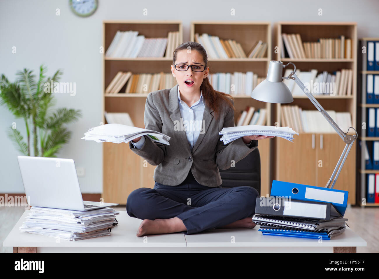 Busy angry businesswoman sitting on the desk in office Stock Photo - Alamy