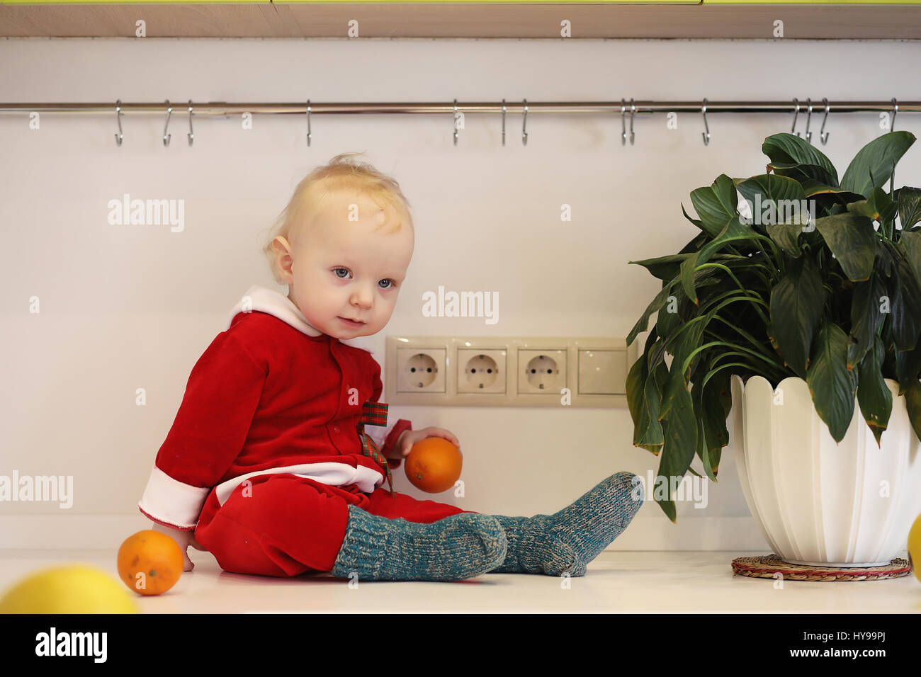 Little child in the kitchen sits on a table Stock Photo - Alamy