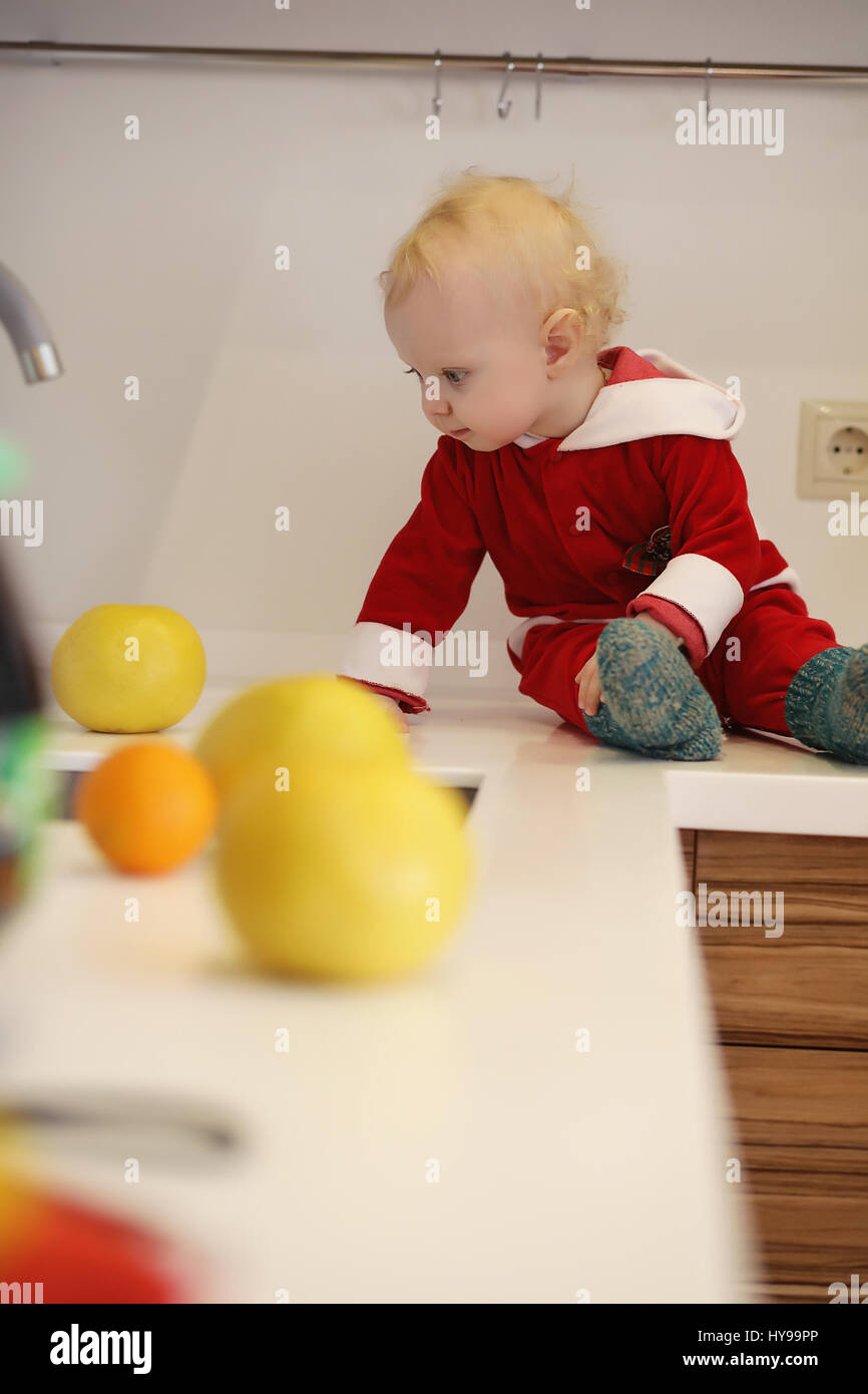 Little child in the kitchen sits on a table Stock Photo - Alamy
