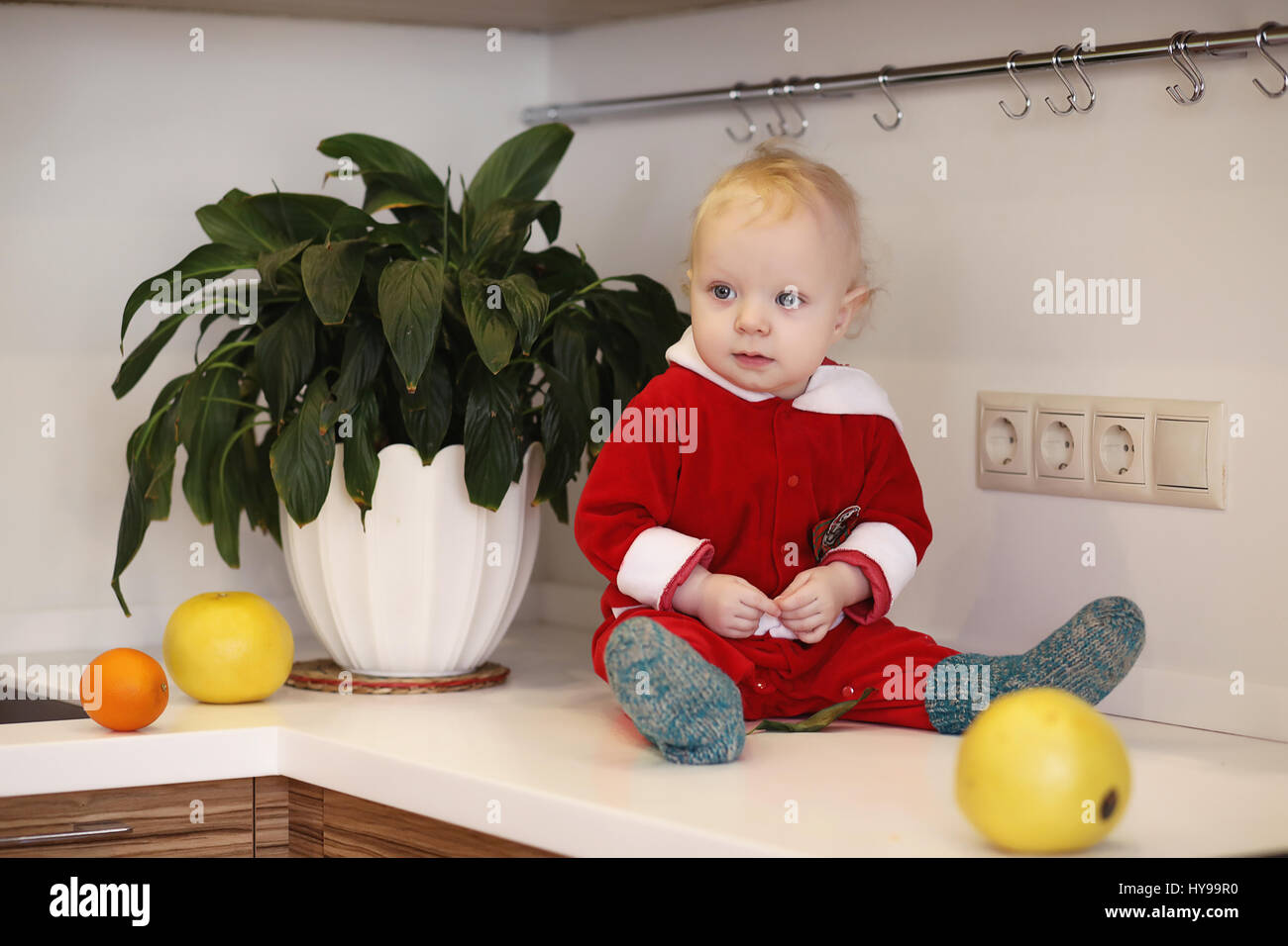 Little child in the kitchen sits on a table Stock Photo - Alamy