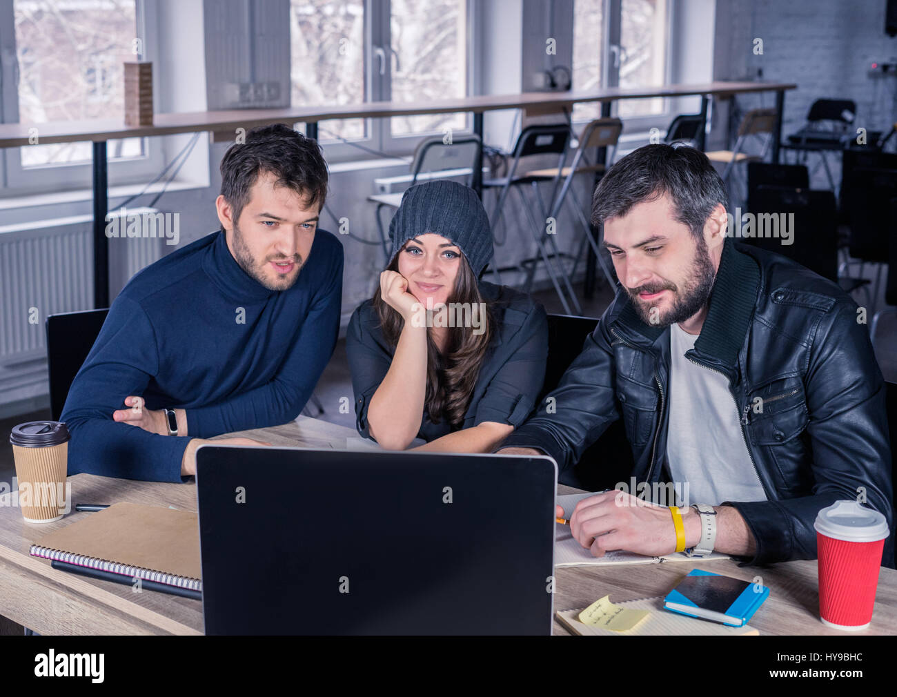 Young smart team. Group of modern people watching project on laptop ...