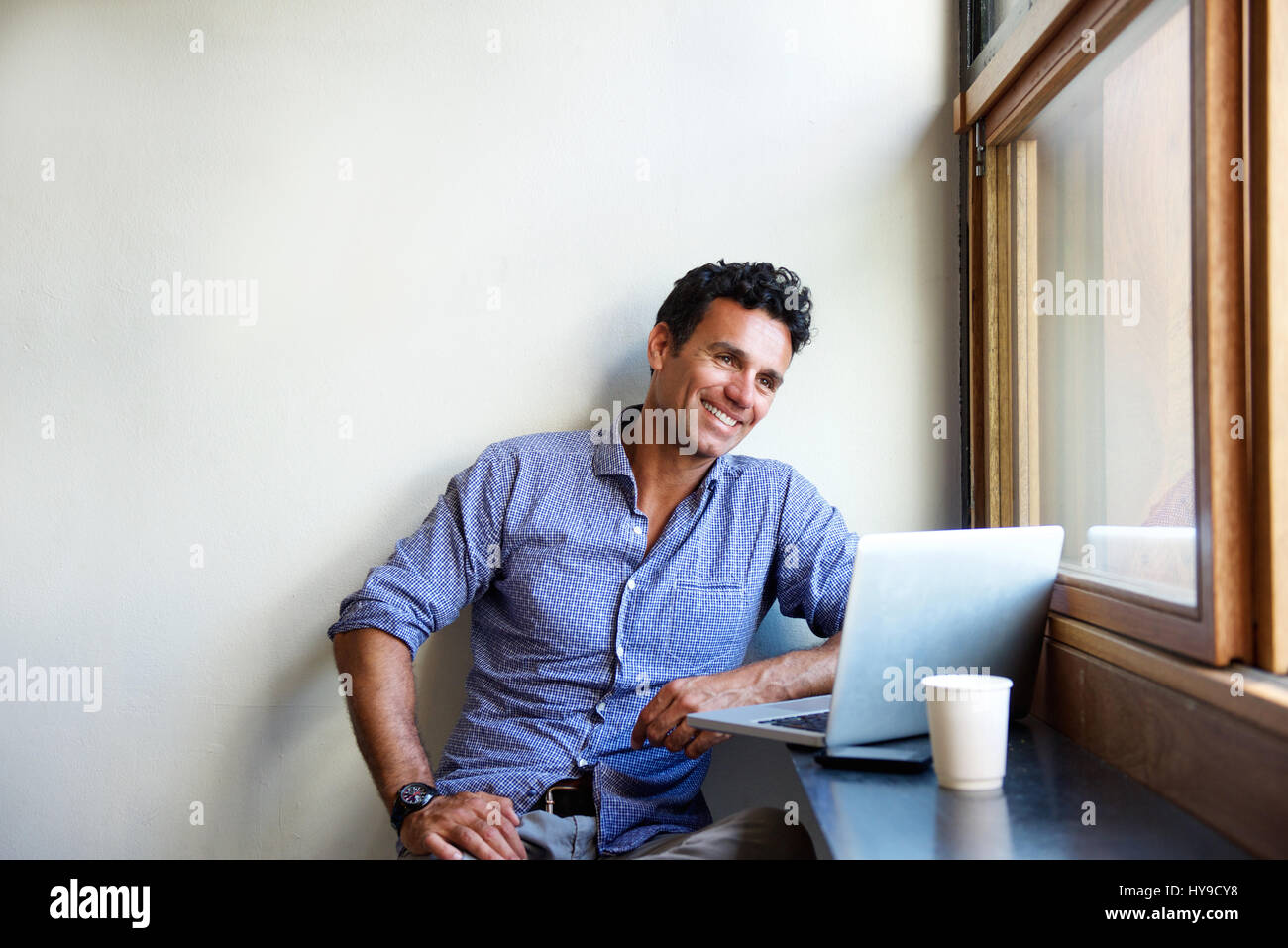 Portrait of a handsome modern man smiling with laptop at cafe Stock ...
