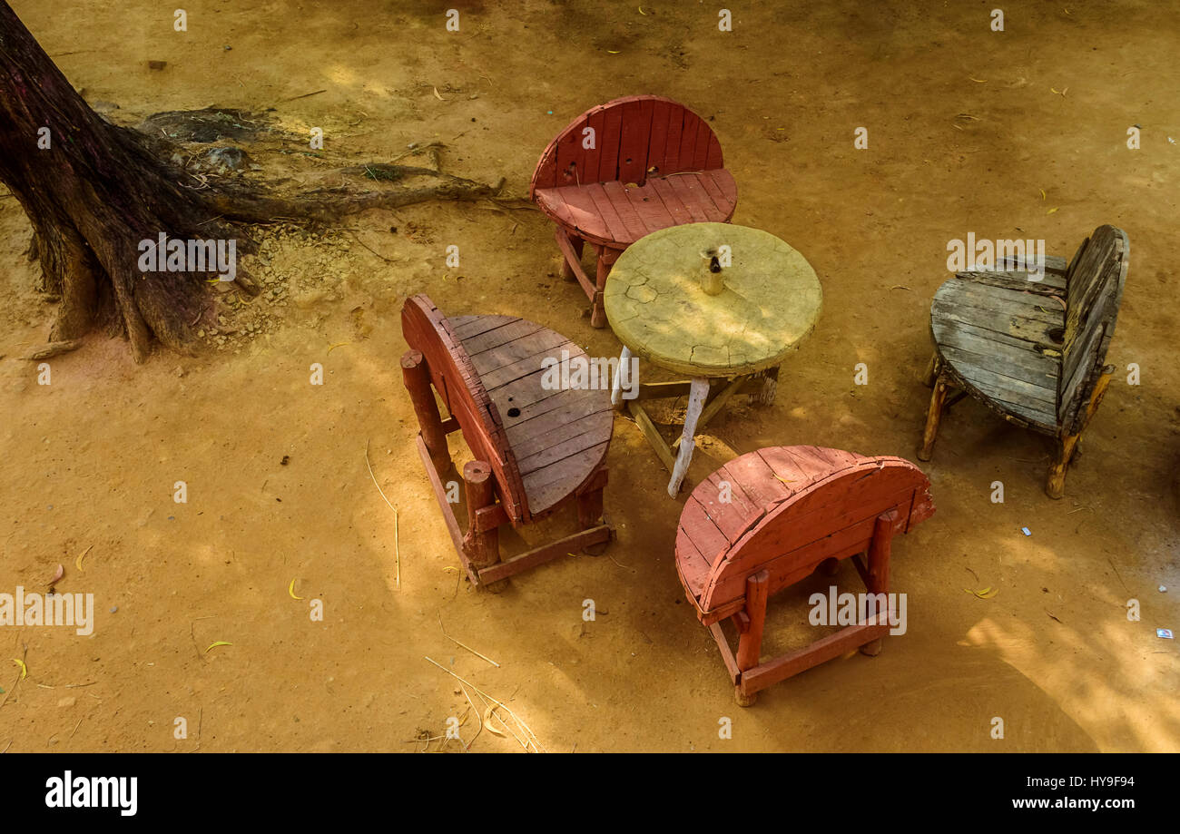 Wood carved table and four empty chairs beside a tree with copy space ...