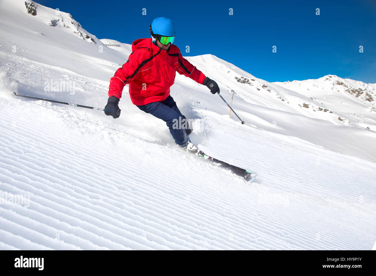 Man skiing on the prepared slope with fresh new powder snow in Alps ...