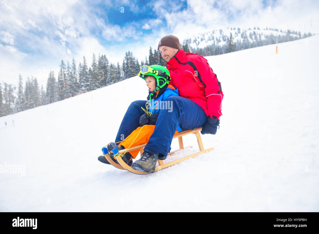 Father and his little son enjoying a sledge ride in famous ski resort ...
