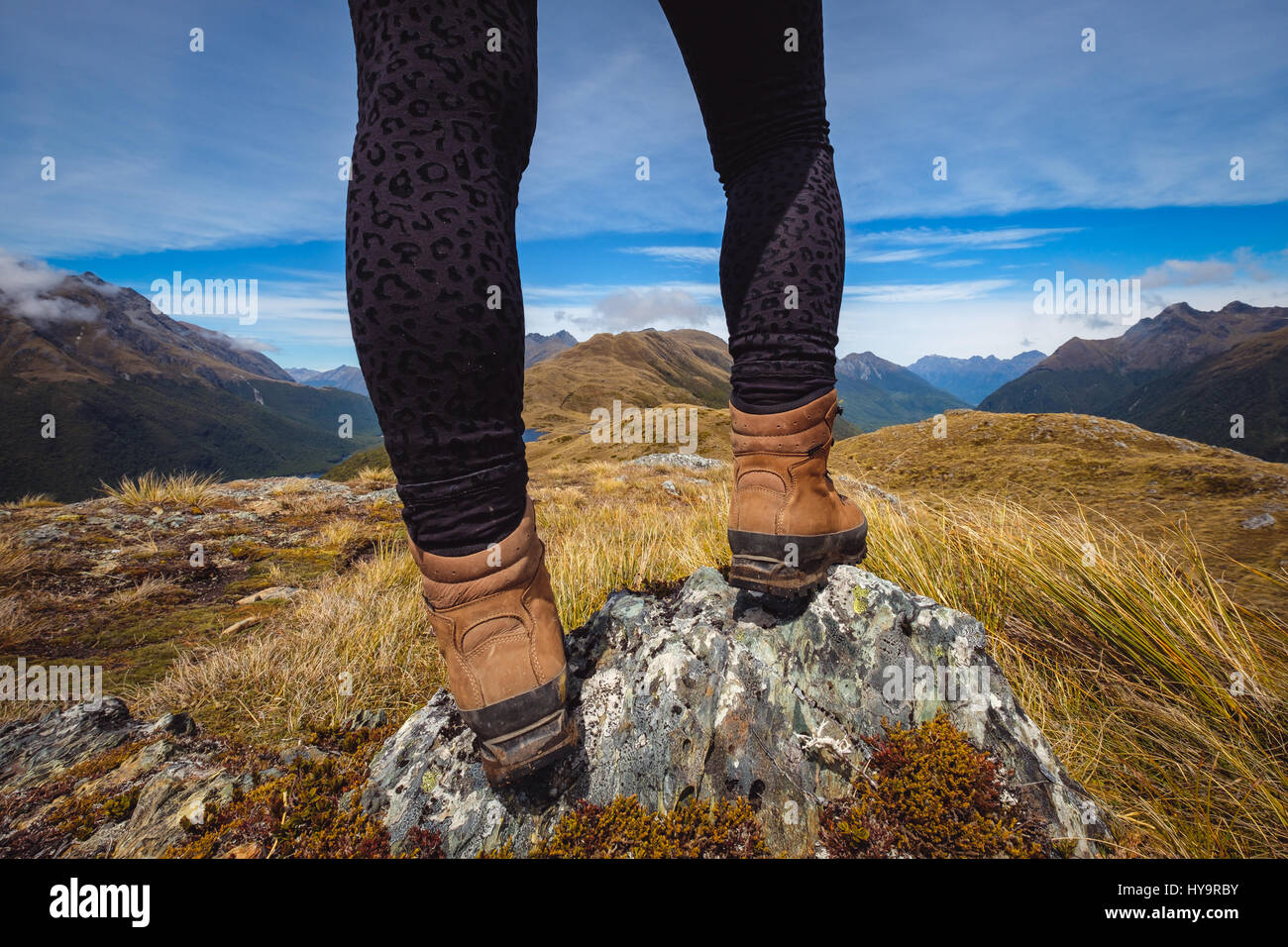 Detail of woman's legs in trekking shoes with mountain range background ...