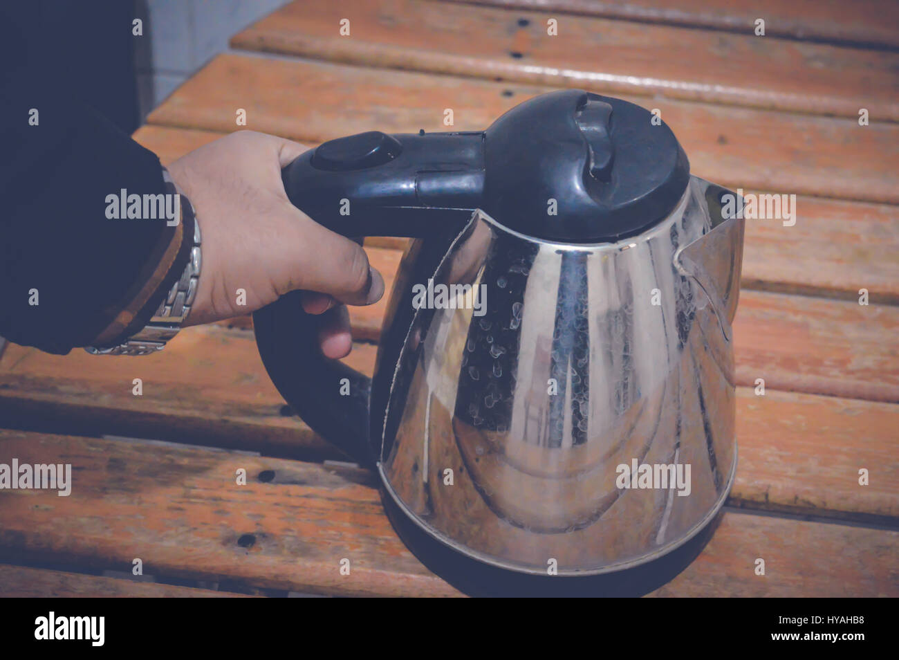 hand holding kettle on wooden table Stock Photo - Alamy