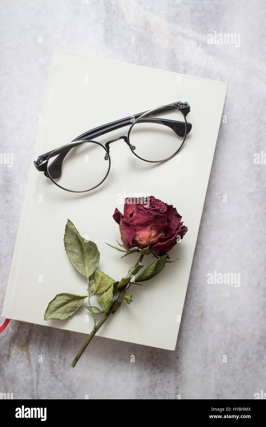Book with beautiful dried rose and glasses, from above Stock Photo - Alamy