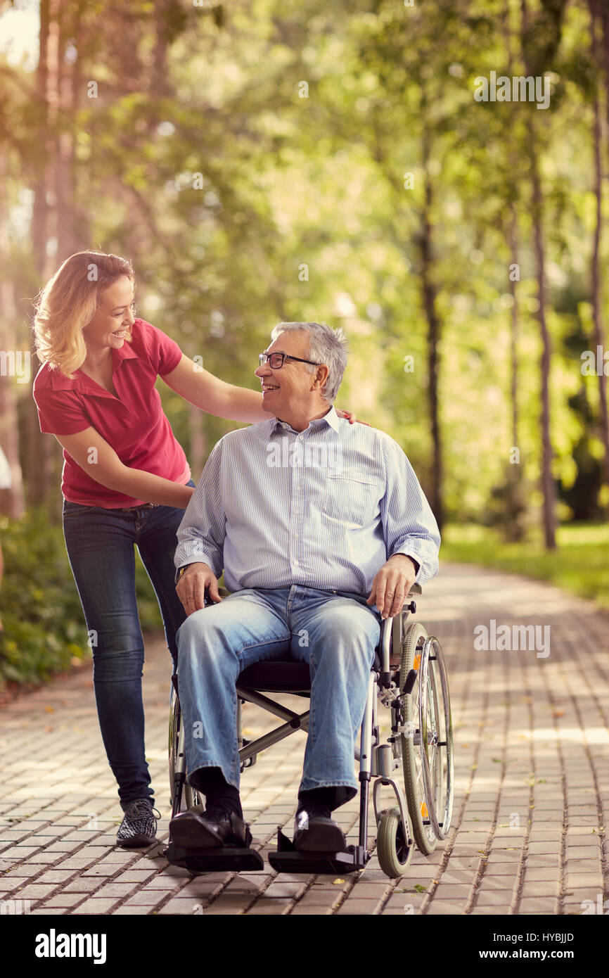 Smiling young woman with her disabled father in wheelchair outdoor ...