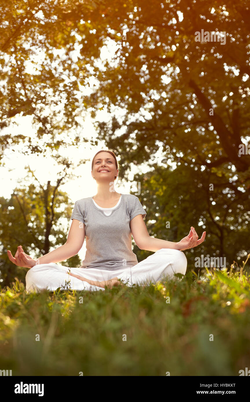 Smiling lady in yoga pose in green nature Stock Photo - Alamy