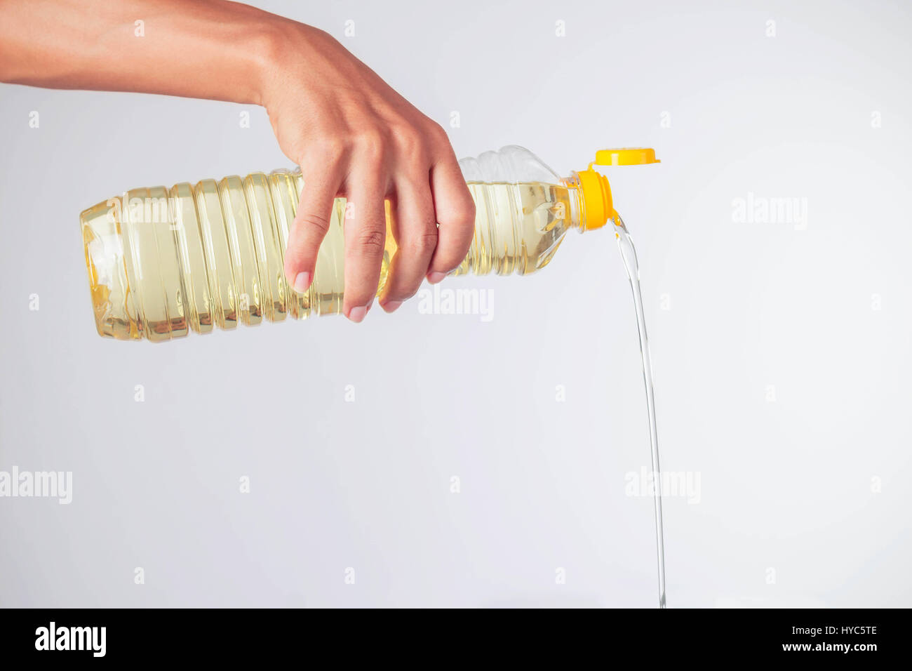 Hand is pouring vegetable oil on a white background Stock Photo - Alamy