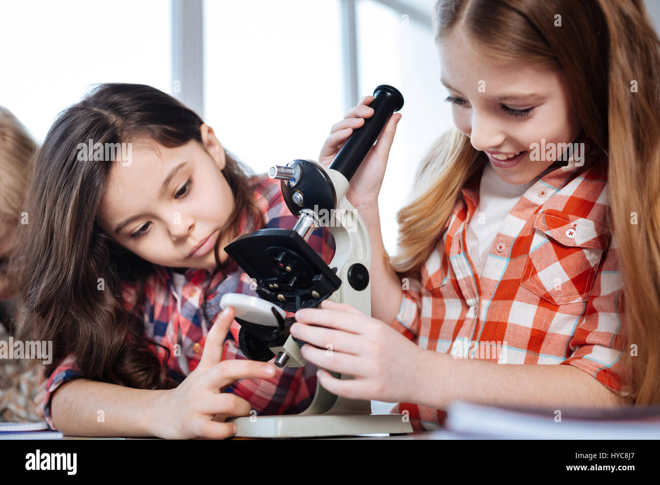 Supportive smart girl helping her friend with experiment Stock Photo ...