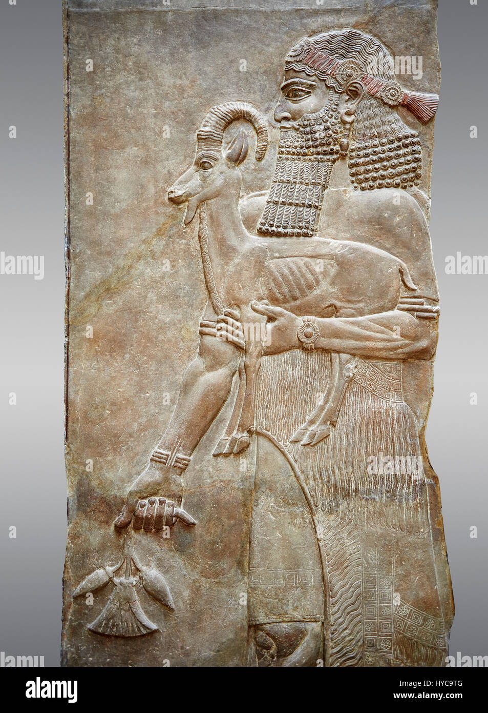 Stone relief sculptured panel of a man holding an Ibex and a poppy ...