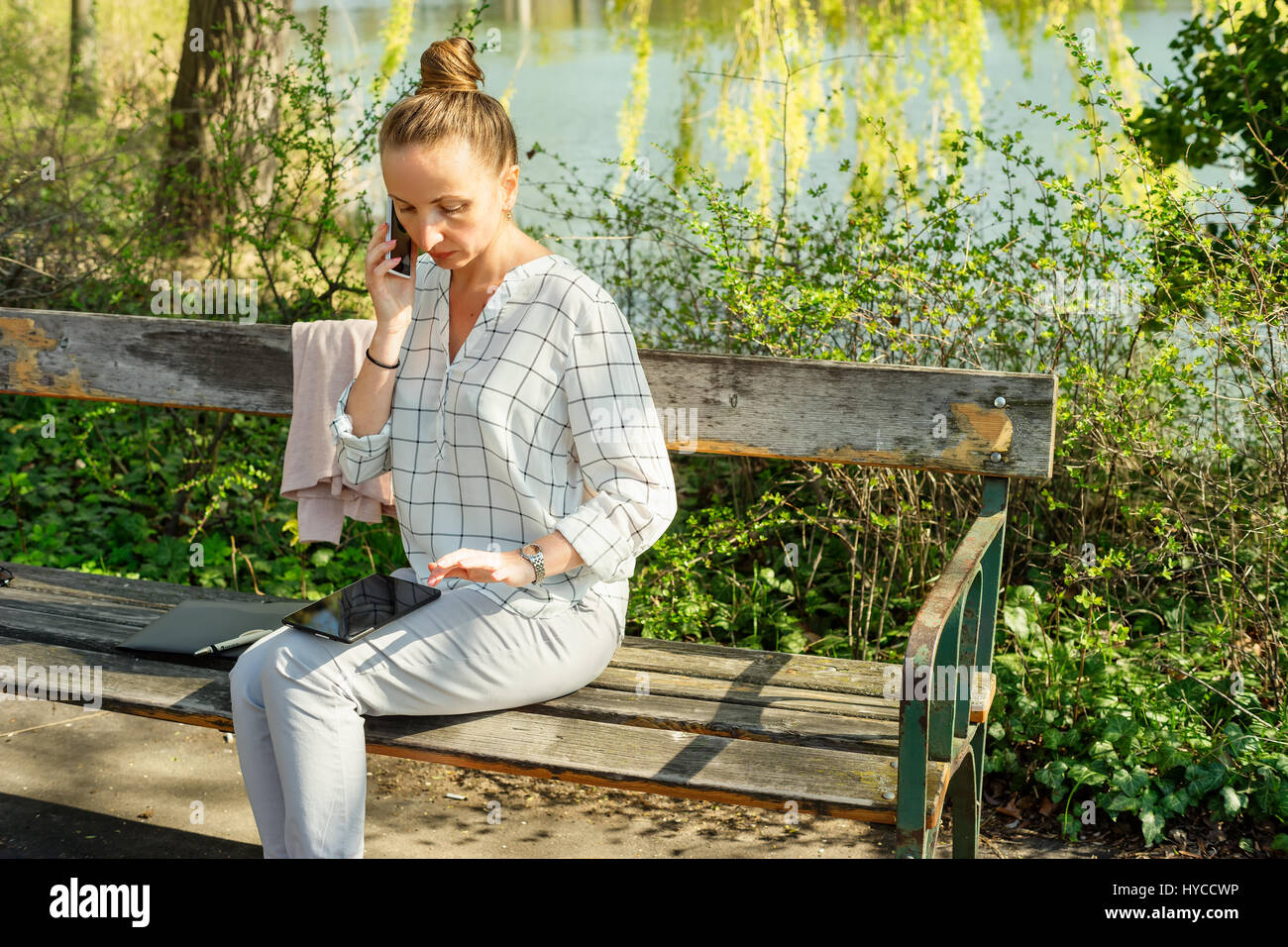 Woman talking phone on bench Stock Photo - Alamy
