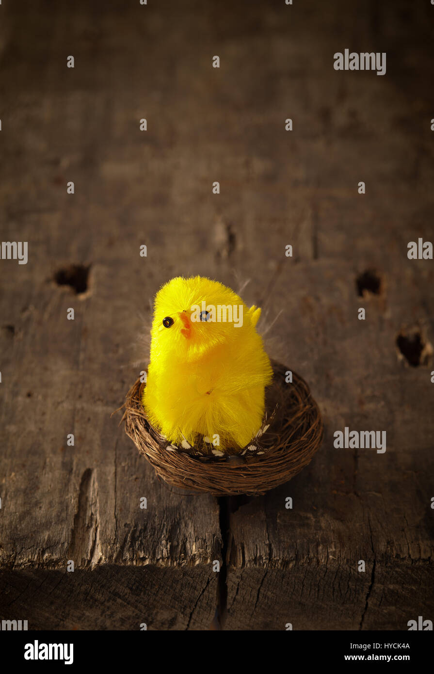 Cute little chicken decoration in a nest on a rustic wooden table ...