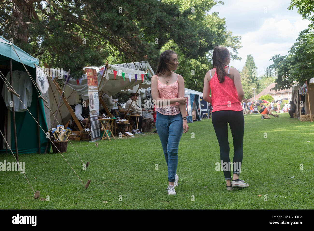 two girls at a country fair with tent and tent pegs to left both ...