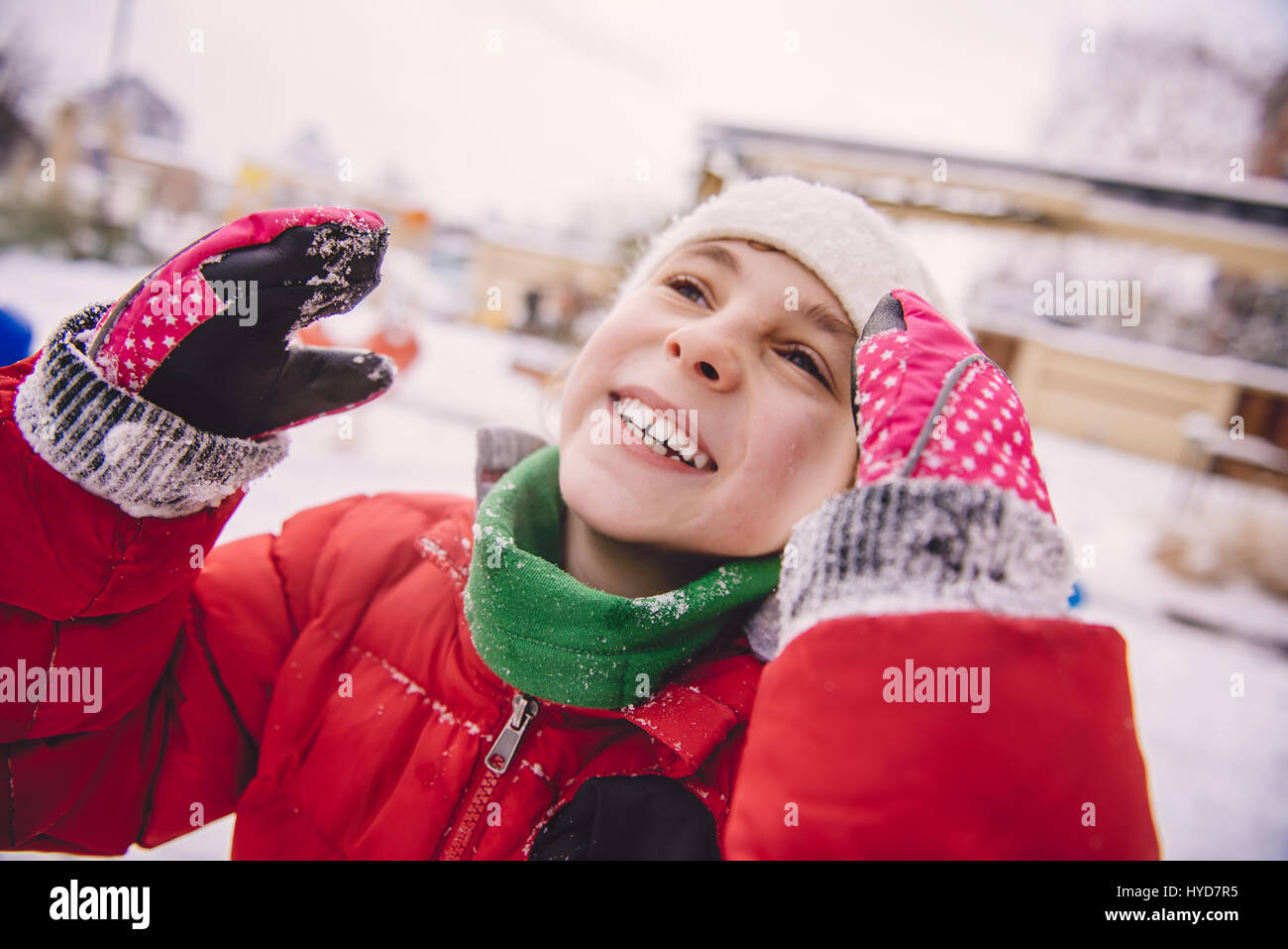 Little girl wearing red jacket and white hat playing in the snow Stock ...
