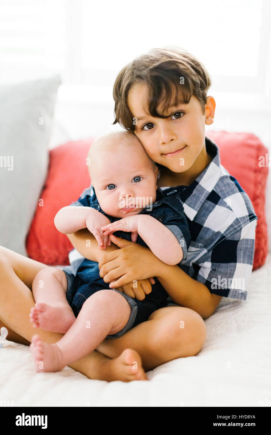 Young boy (6-7) holding brother (2-5 months Stock Photo - Alamy