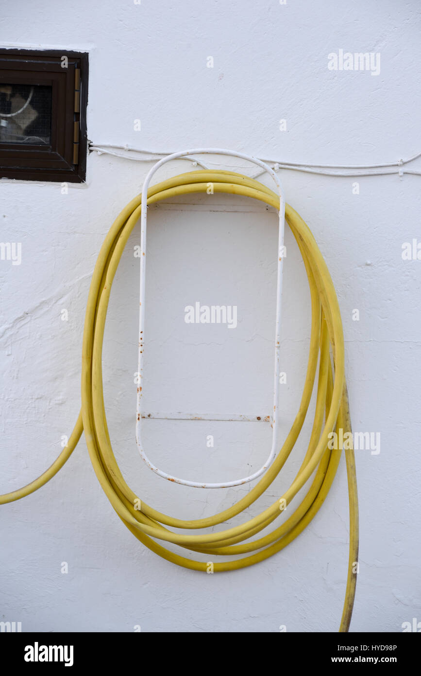 Yellow water pipe hose on the wall connected to water source Stock ...