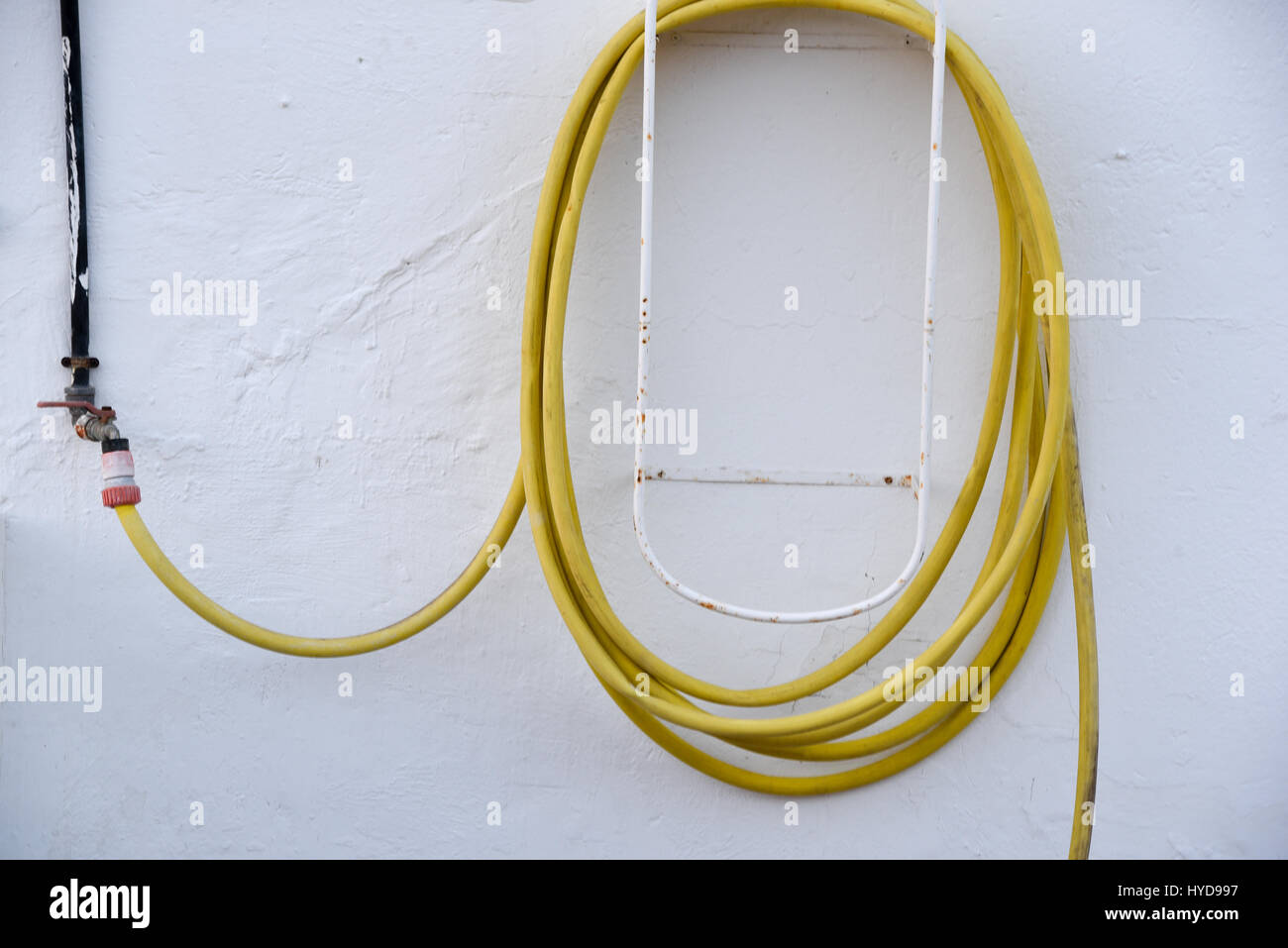 Yellow water pipe hose on the wall connected to water source Stock ...